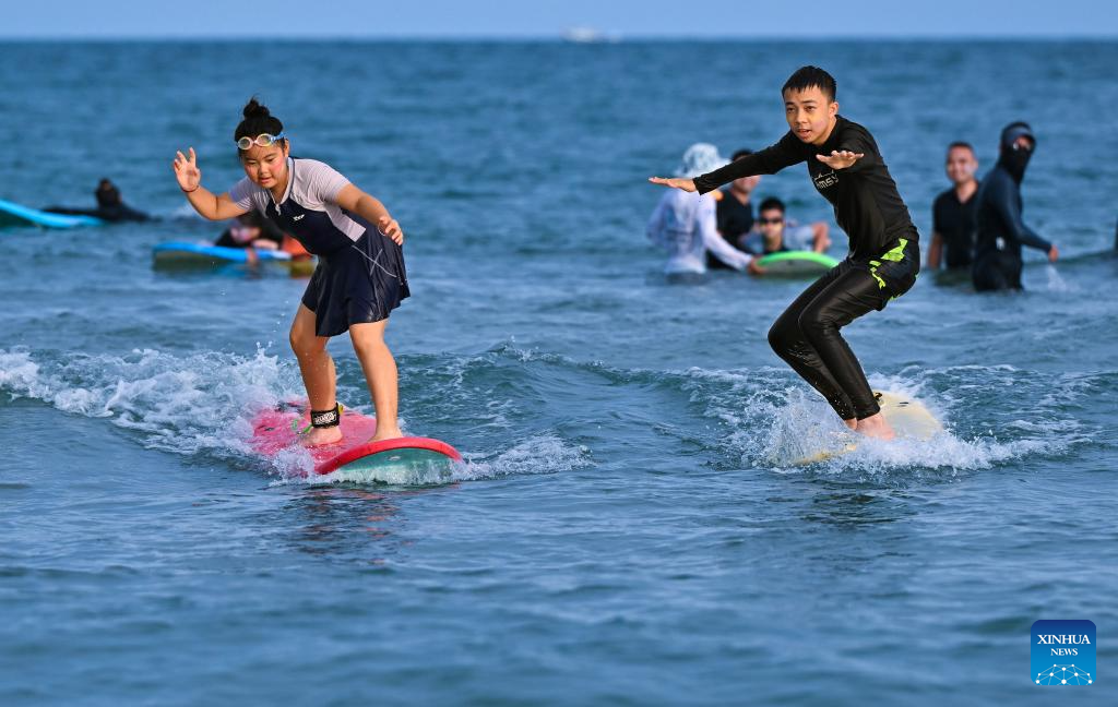 Tourists surf at Riyue Bay in Wanning, S China's Hainan-Xinhua