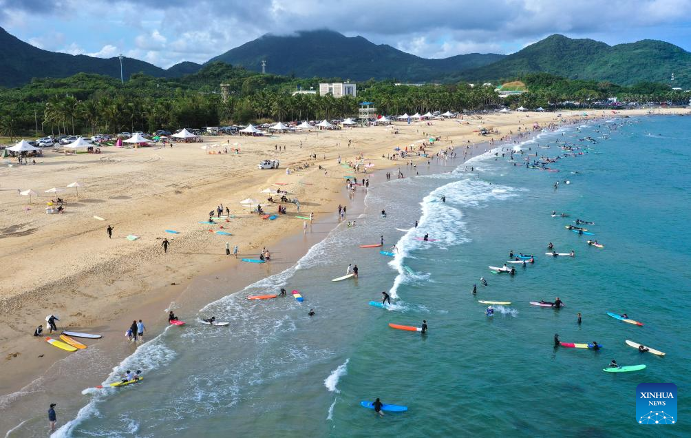 Tourists surf at Riyue Bay in Wanning, S China's Hainan-Xinhua